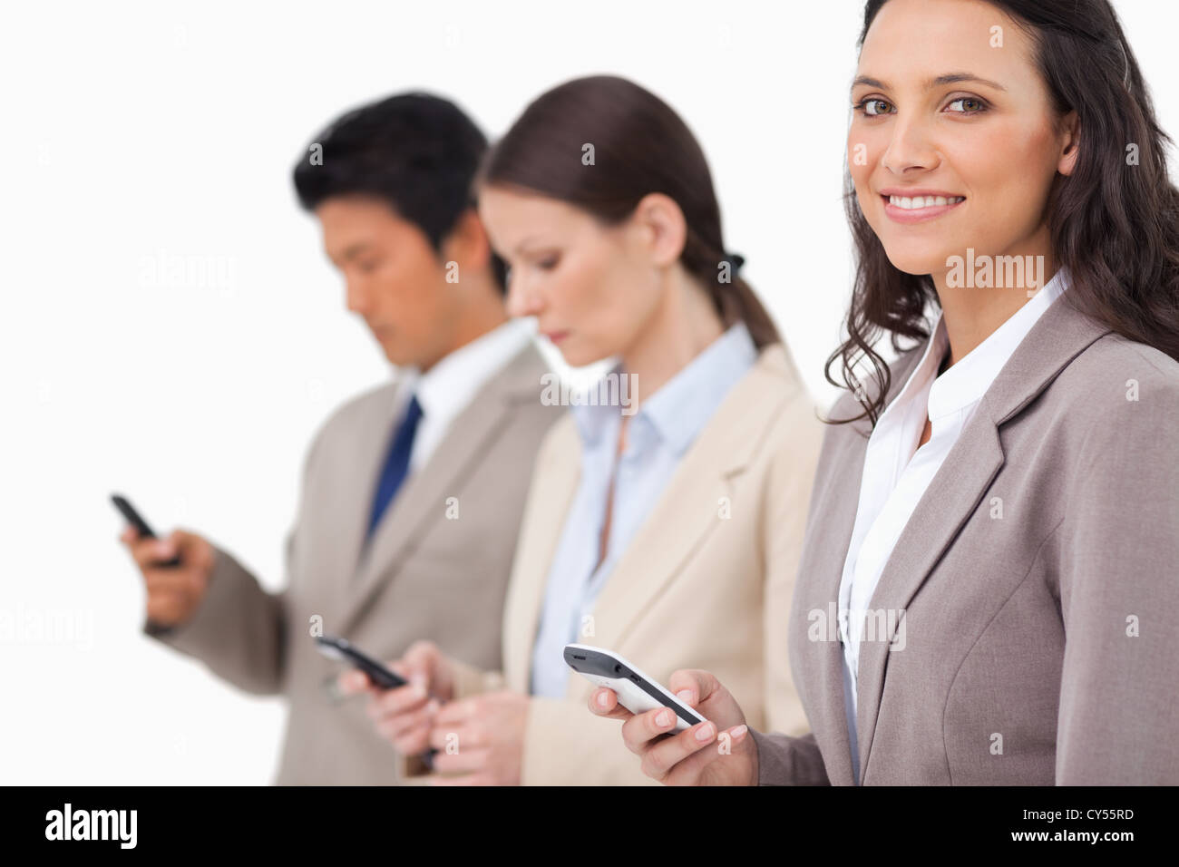 Smiling saleswoman with cellphone next to colleagues Stock Photo - Alamy