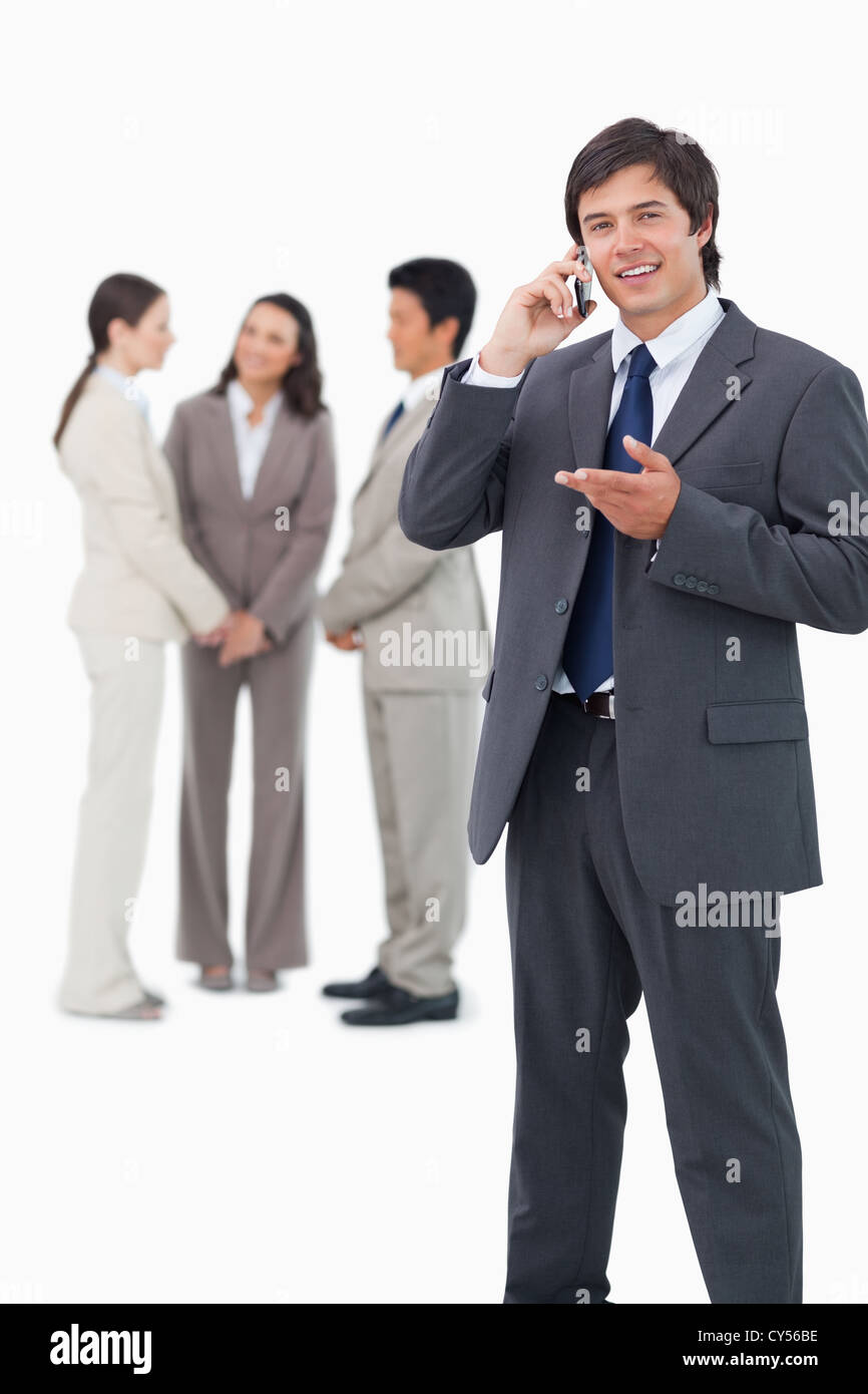 Salesman talking on cellphone with team behind him Stock Photo - Alamy