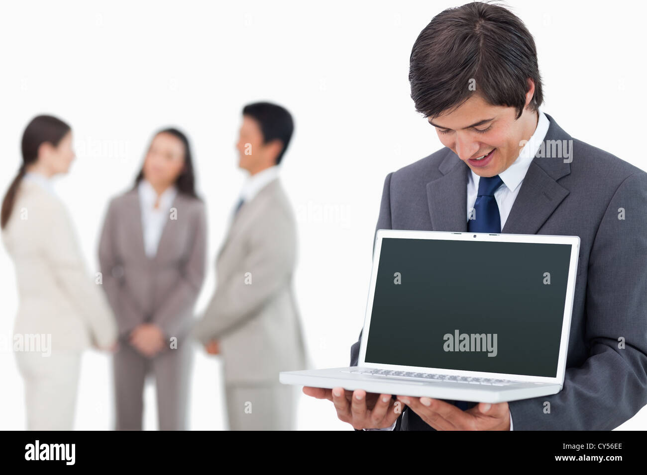 Salesman showing laptop screen with team behind him Stock Photo - Alamy