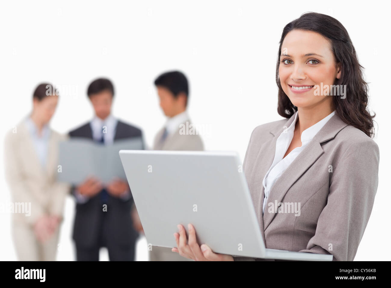Smiling saleswoman with laptop and colleagues behind her Stock Photo ...