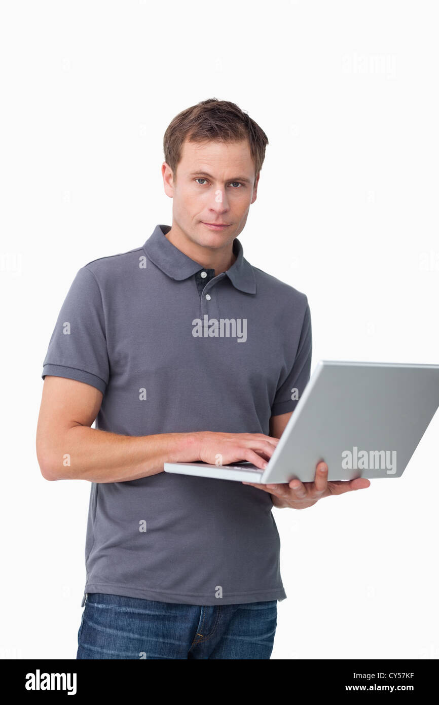 Young man standing with his laptop Stock Photo - Alamy