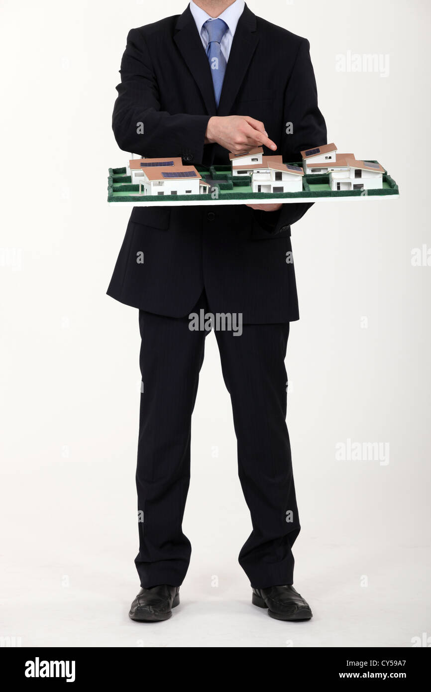 Property salesman pointing at model housing Stock Photo - Alamy