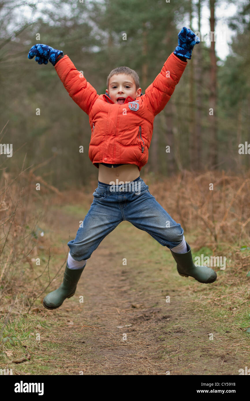 Boy preforming a star jump on a woodland walk Stock Photo - Alamy