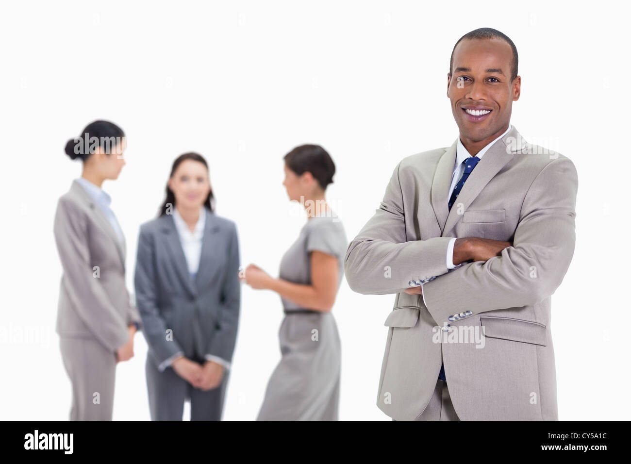 Businessman smiling with three co-workers talking in the background ...