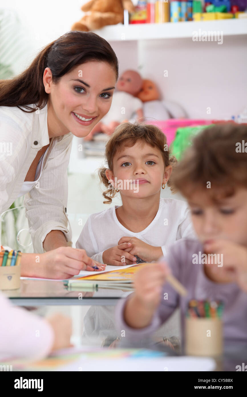 Young teacher and children in a classroom Stock Photo - Alamy