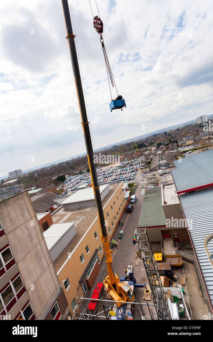 Looking down on mobile crane lifting onto roof of five story hospital ...