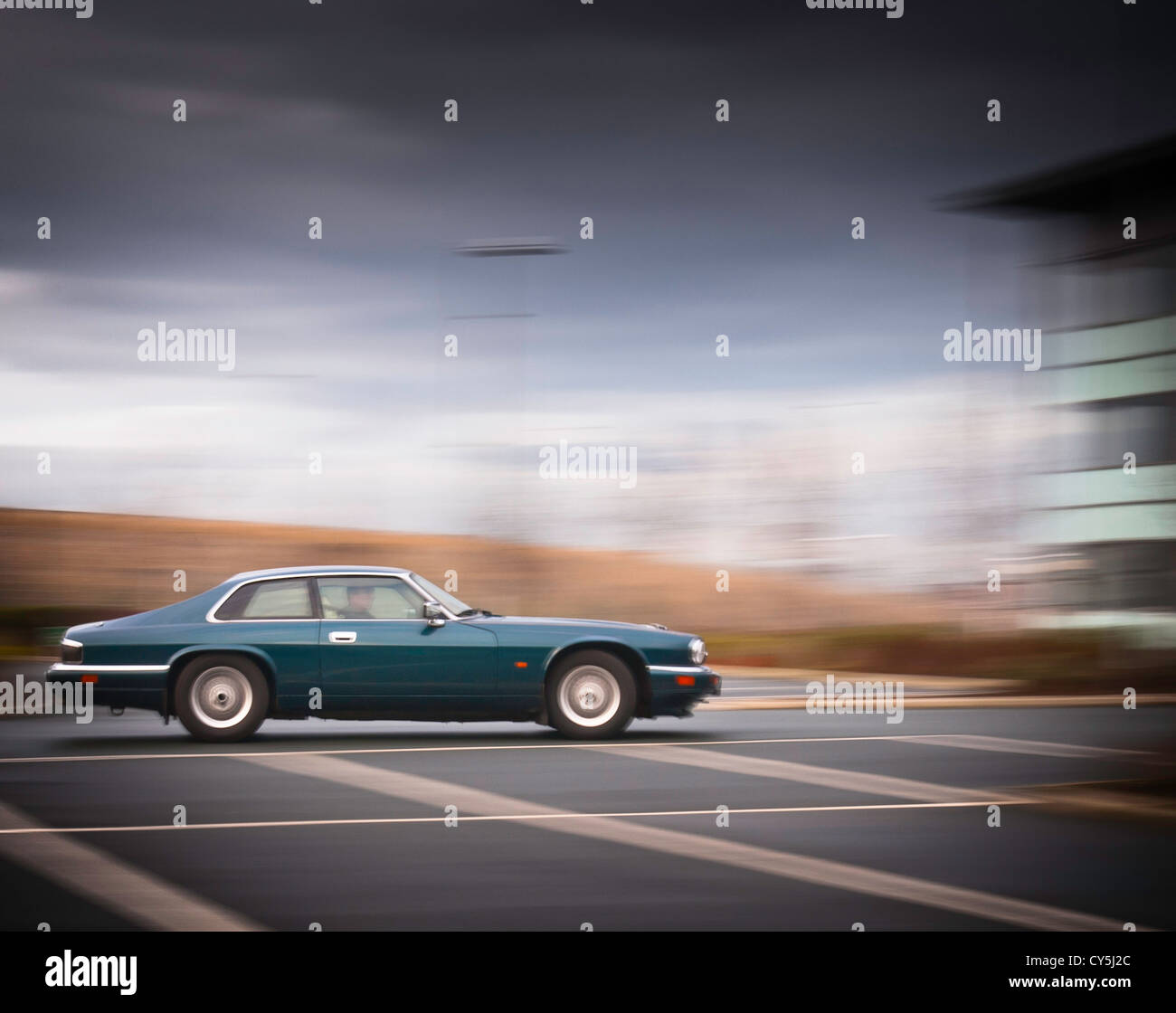 Creative image of a classic sports car driving through an office car ...