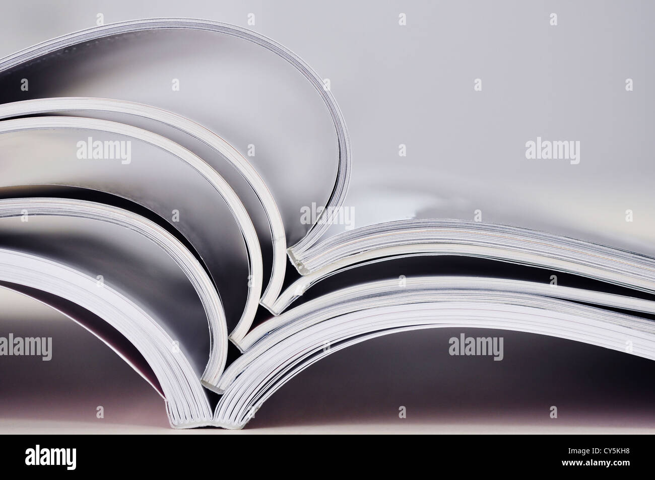 Closeup background of a pile of old magazines with bending pages. Small ...