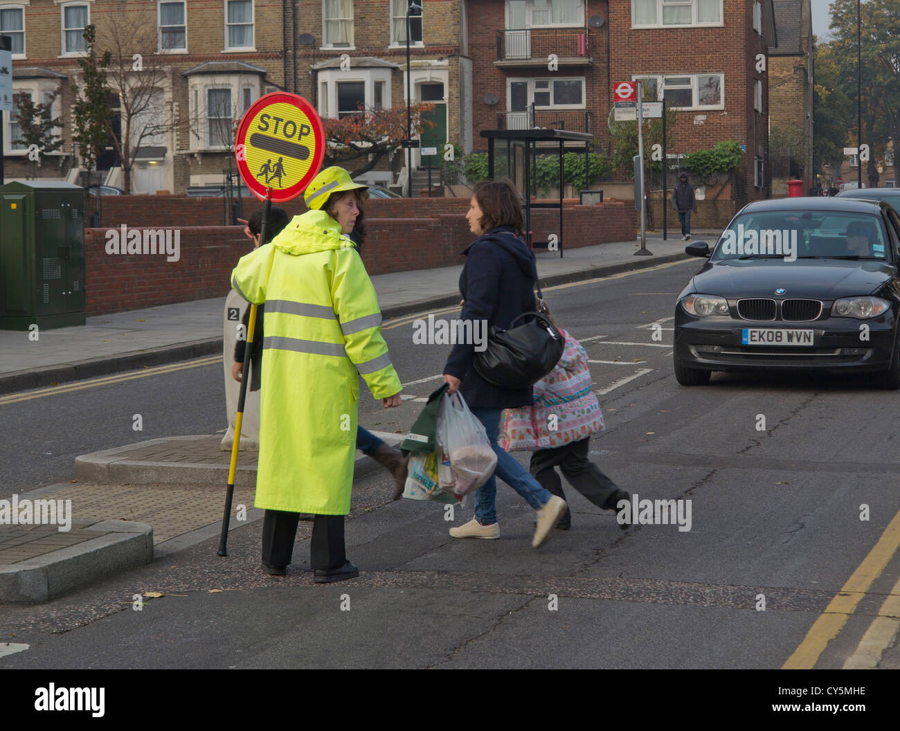 Traffic assistance Lollipop lady road crossing guard helps mother and ...