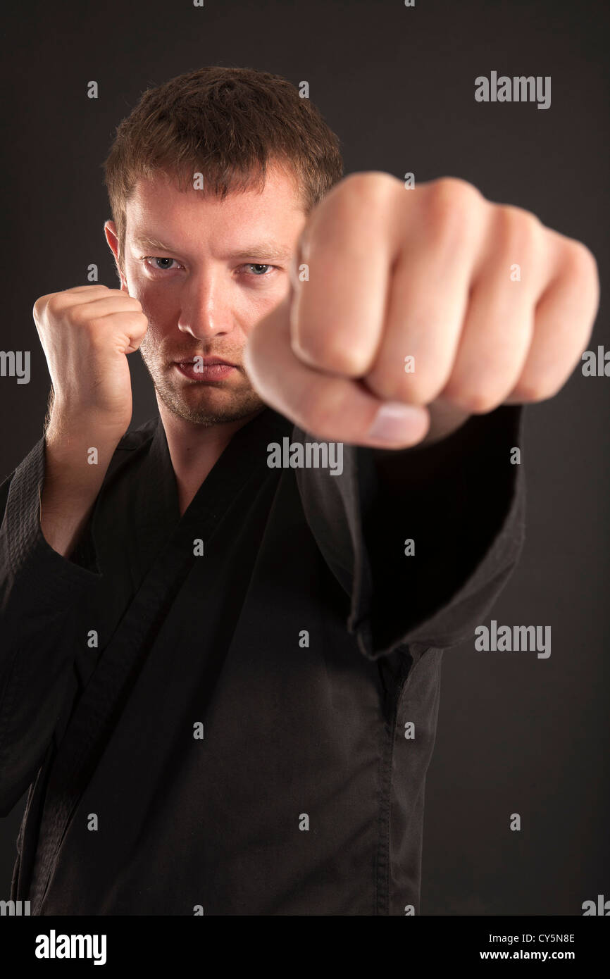 man in black kimono practicing self defense pushing fist towards camera ...