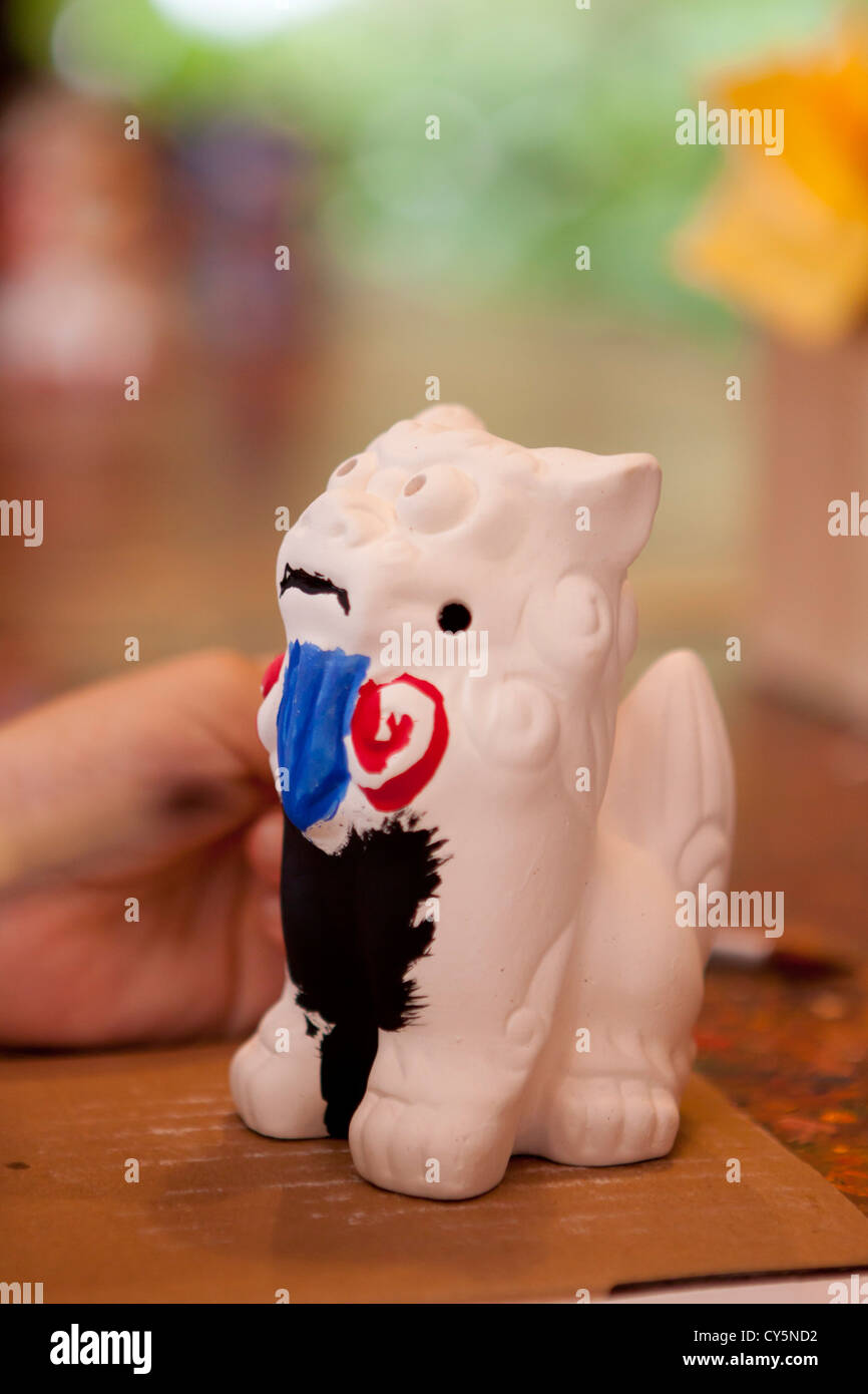 A young boy paints a pottery Shiisa - the stone lion god of Okinawa ...