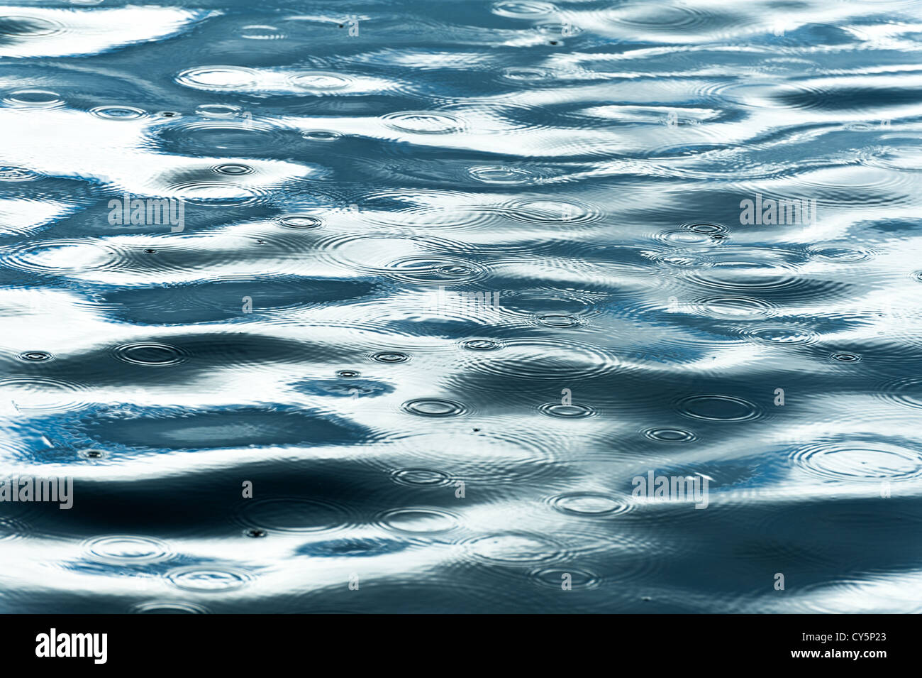 Rain drops falling on lake surface nice dark blue color Stock Photo - Alamy