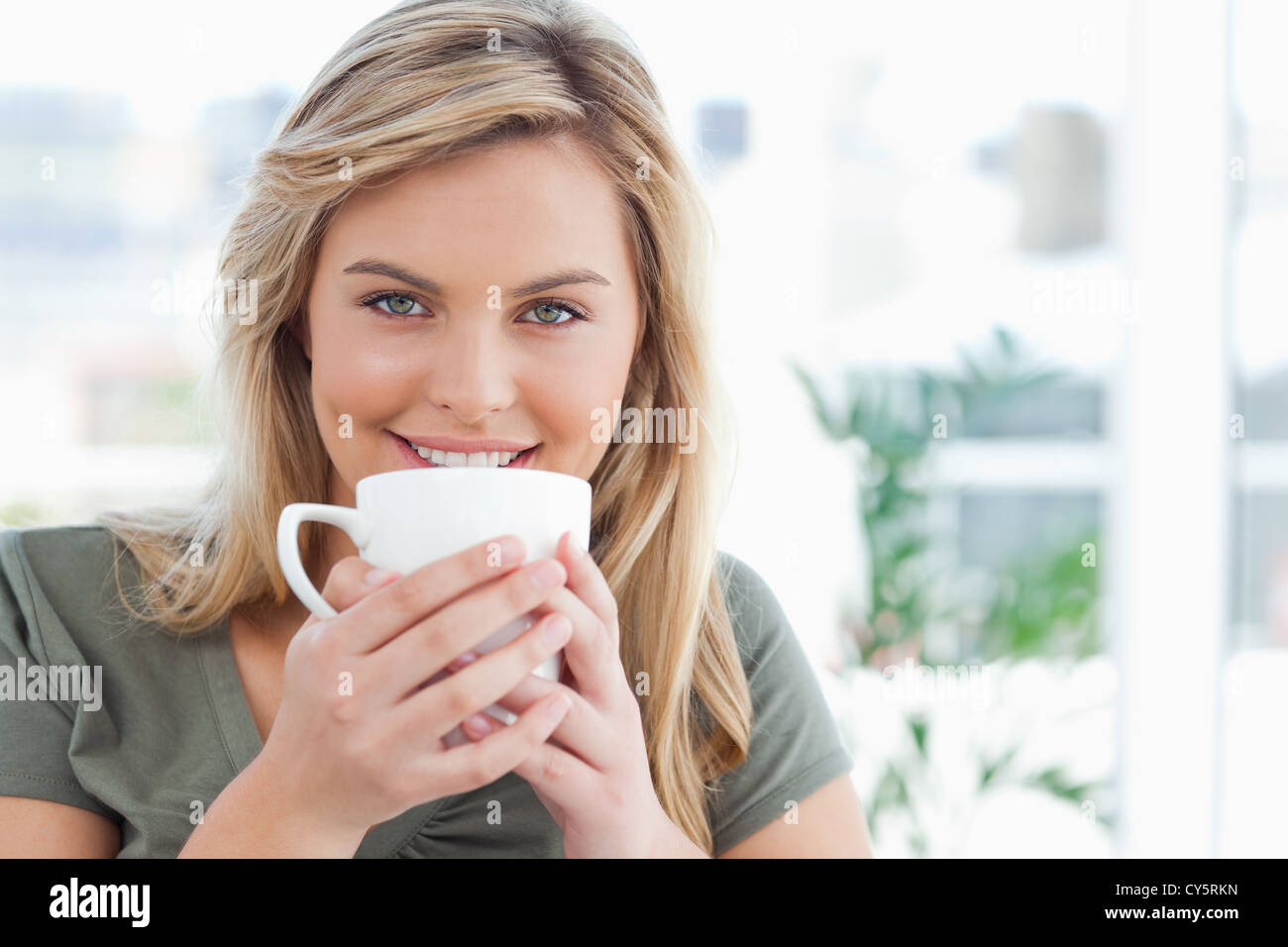 Woman looking forward, smiling with a mug up to near her mouth Stock ...