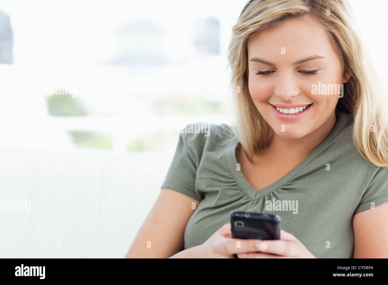 A woman looking at her phone in front of her and smiling Stock Photo ...