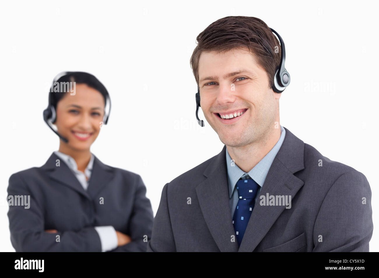 Close up of smiling male call center agent with colleague behind him ...