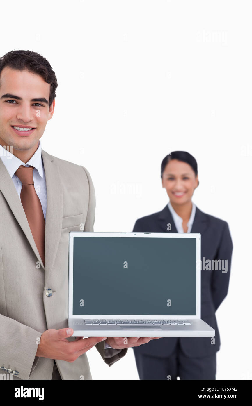 Laptop being presented by smiling salesman with colleague behind him ...
