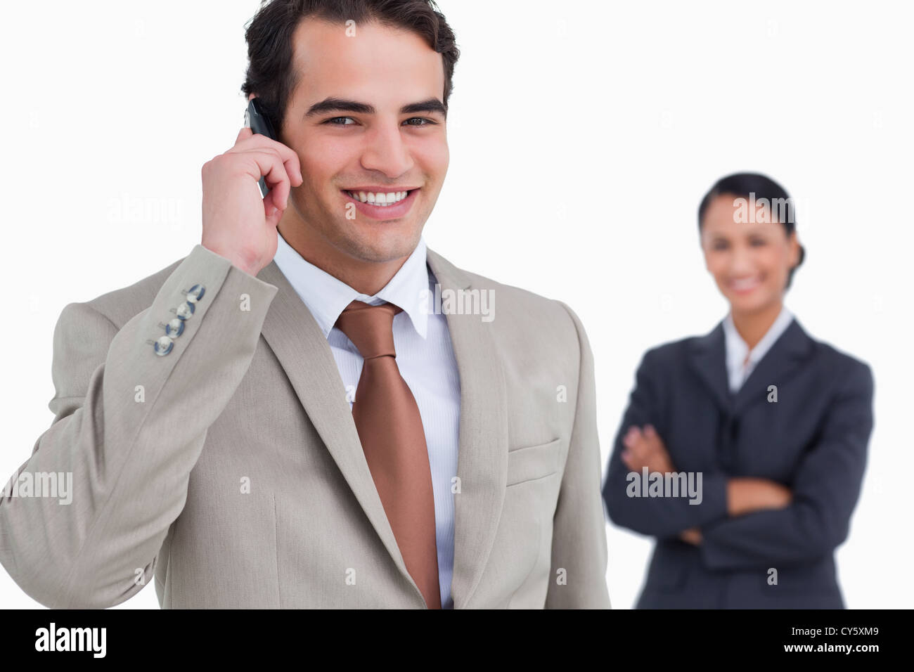 Salesman on his cellphone with colleague behind him Stock Photo - Alamy