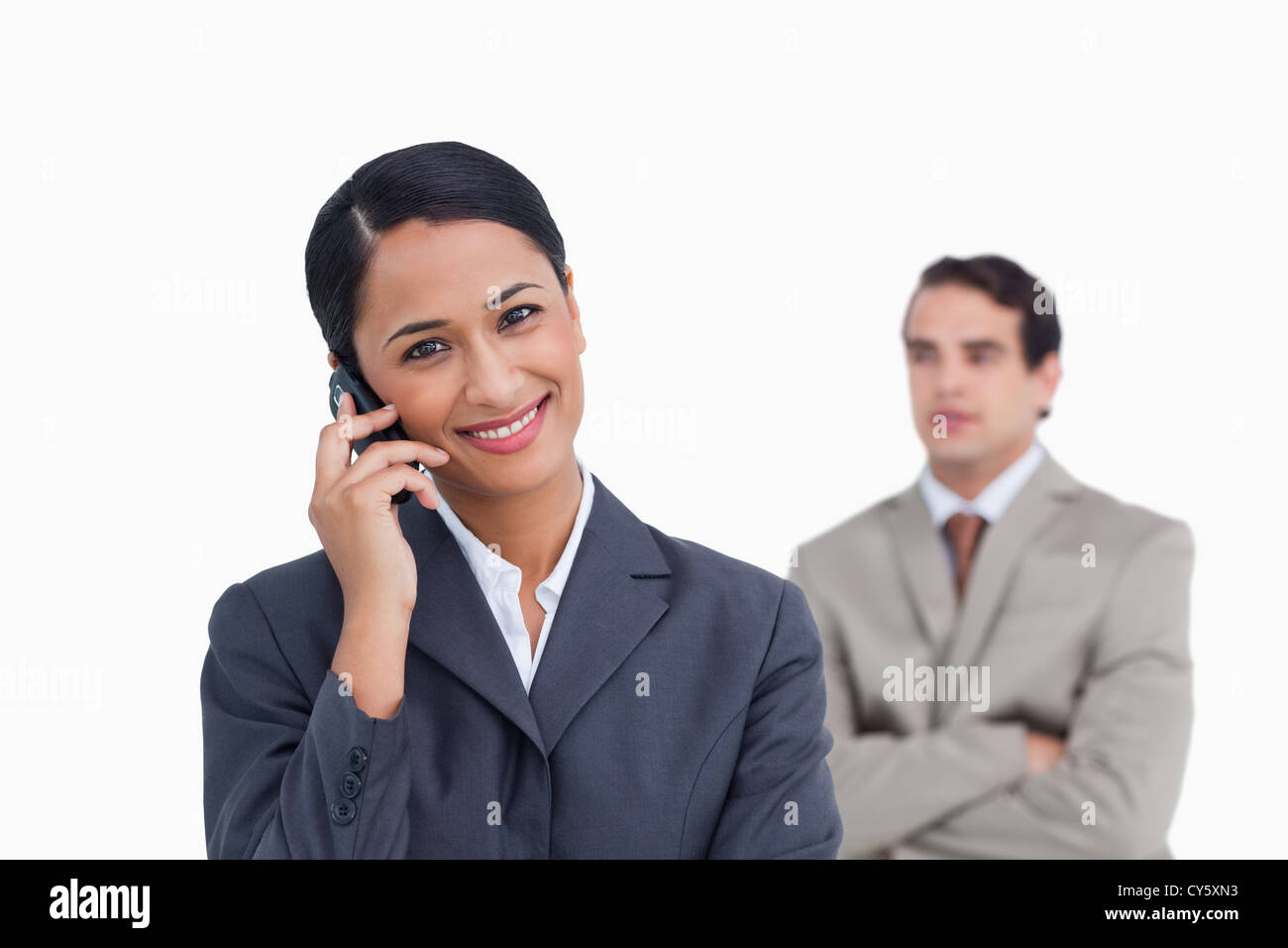 Smiling saleswoman on her mobile phone and colleague behind her Stock ...