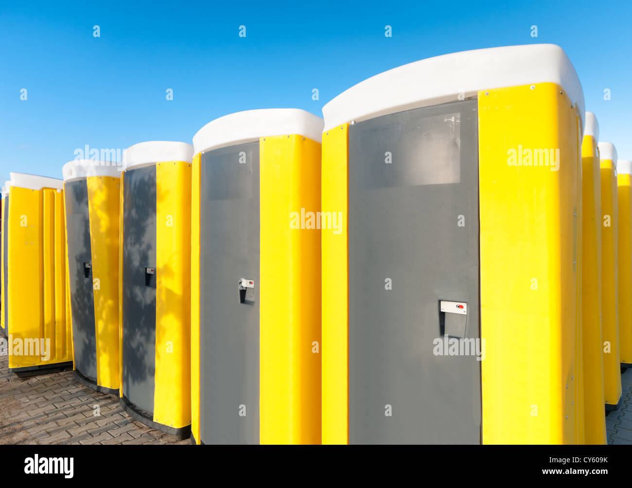 yellow portable toilets under a nice cloudy sky Stock Photo - Alamy