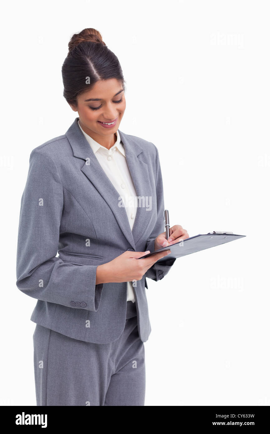 Smiling female entrepreneur taking notes on clipboard Stock Photo - Alamy