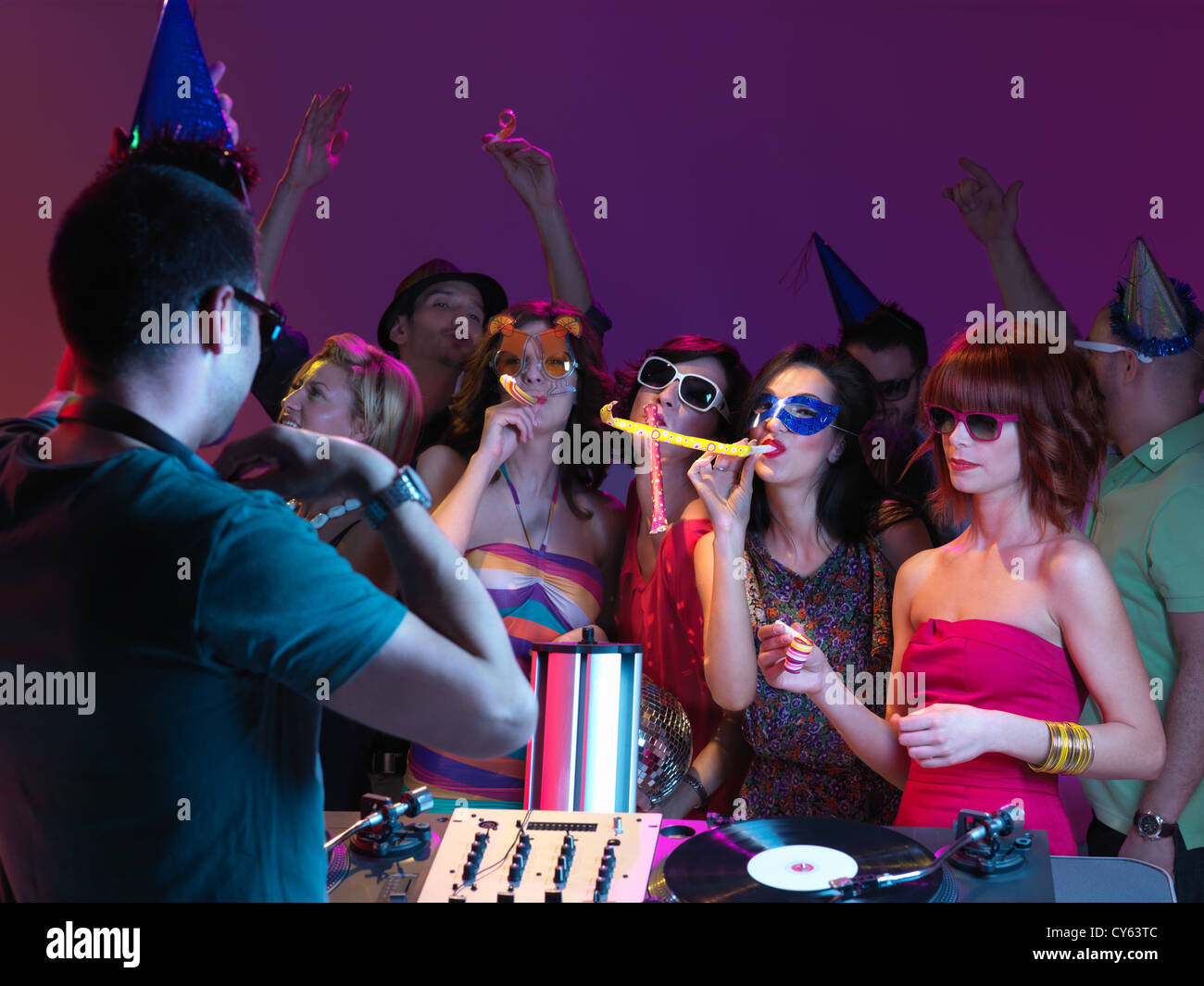 young people having fun at party, playing tith horns and dancing, with ...