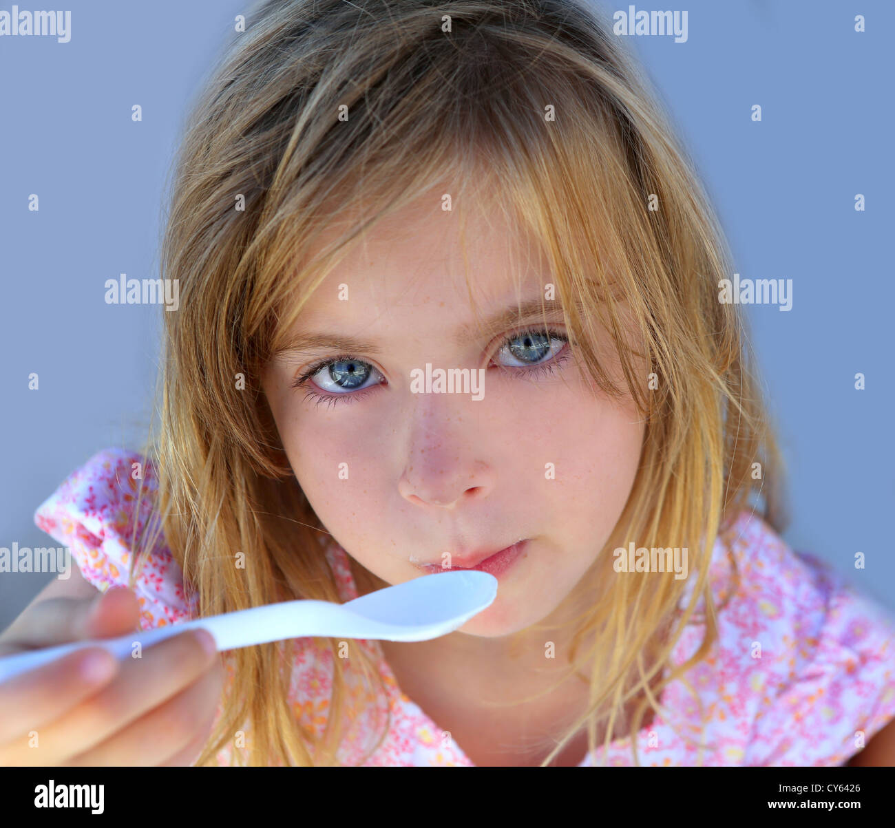 Blue eyes kid girl eating breakfast with spoon portrait Stock Photo - Alamy