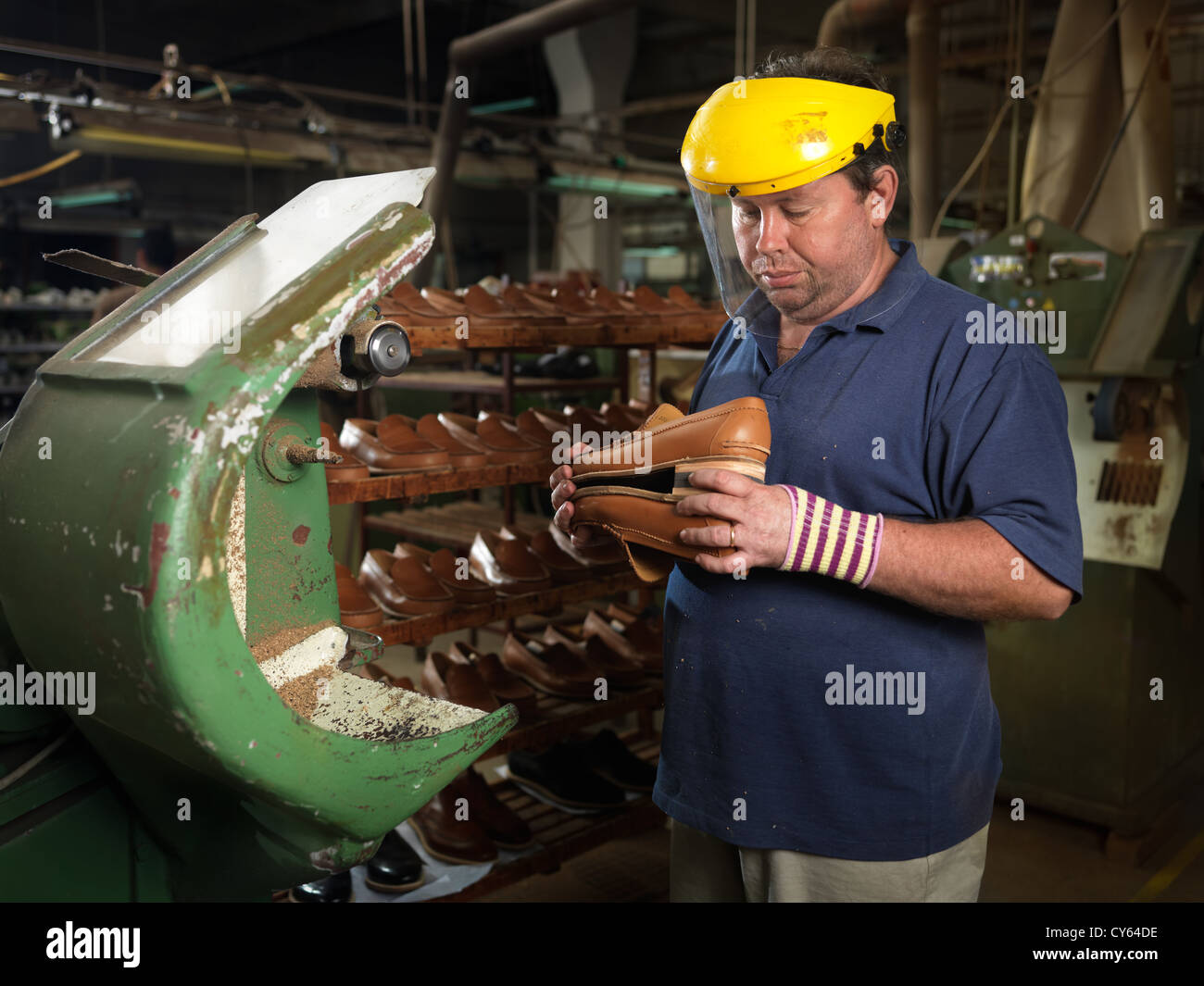 adult man working in a shoe factory, comparing the soles of two shoes ...
