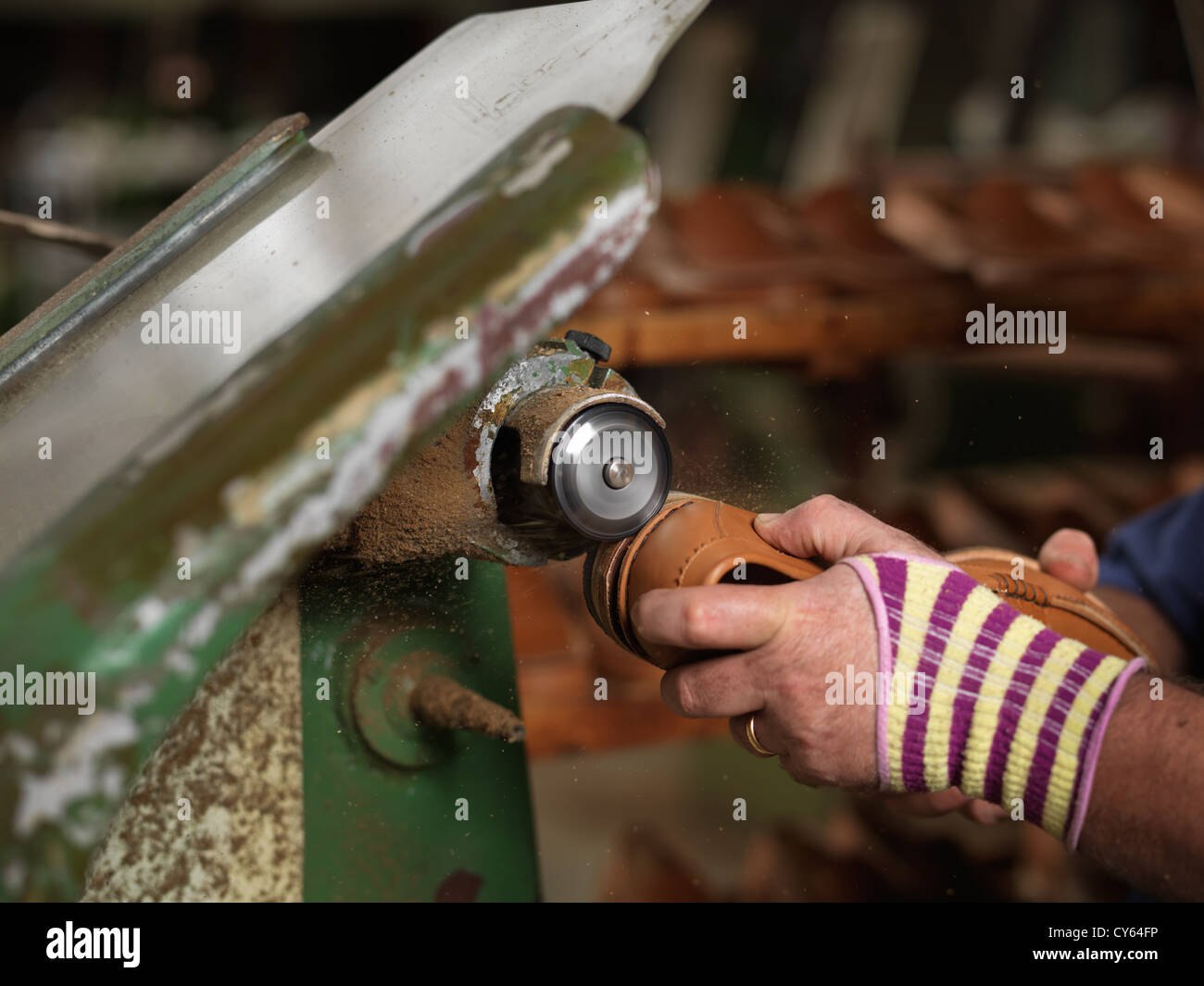 adult man working in a shoe factory, finishing the soles of the shoes ...