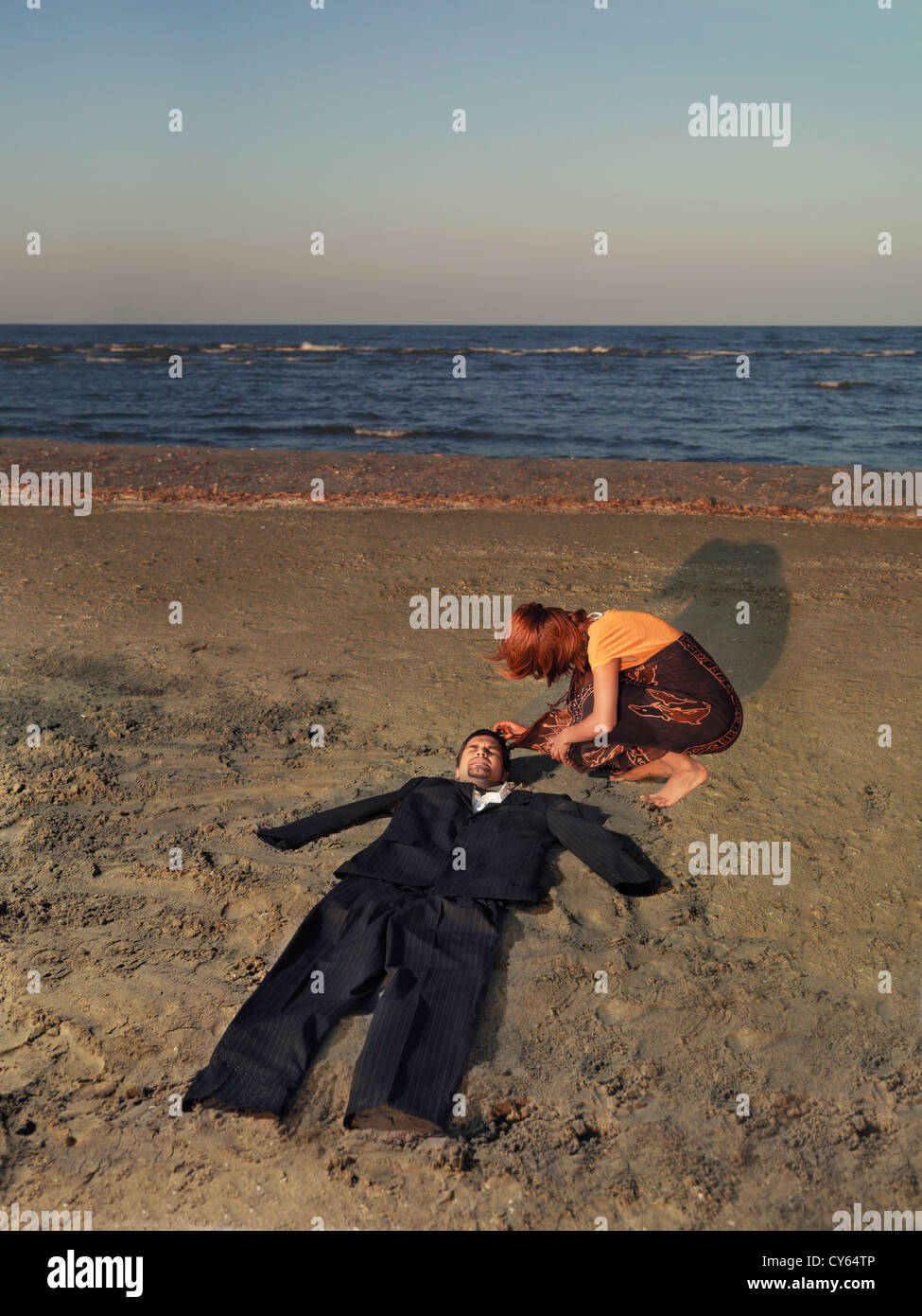 exhausted young businessman stranded on sea shore, with an empty suit ...