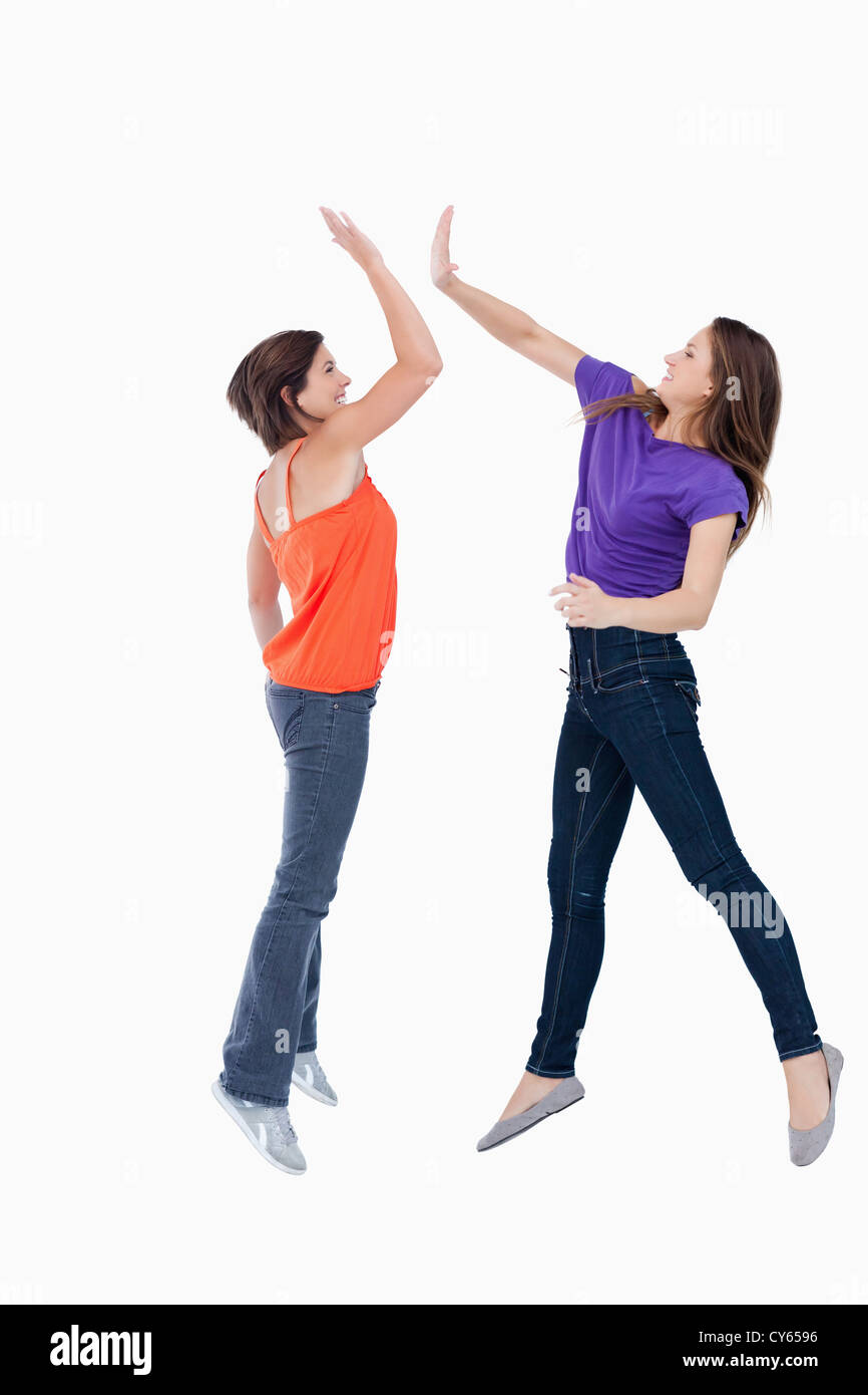 Two teenagers jumping while trying to join their hands Stock Photo - Alamy