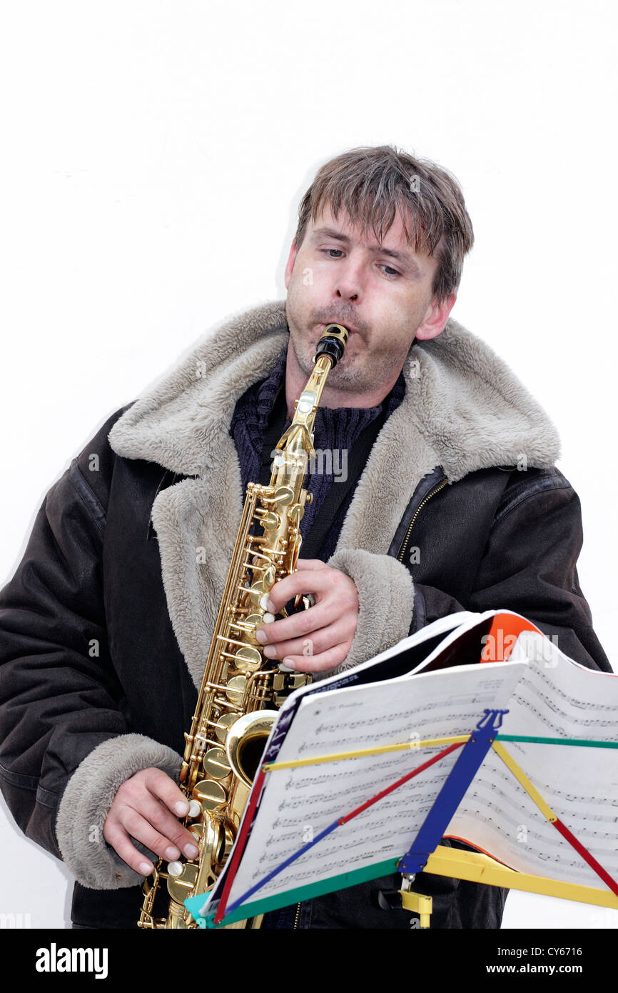 A male busker playing saxophone on a street in Bangor, North Wales ...
