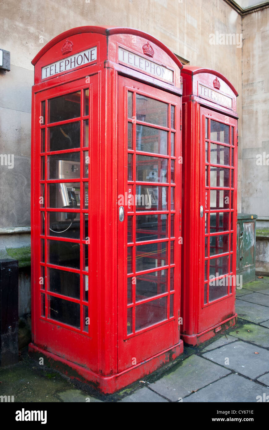 Two red telephone boxes next to each other on stone flagged pavement ...