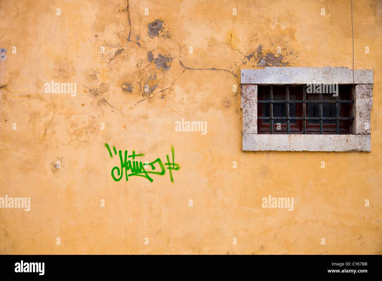 Window on a rendered wall with weather beaten cladding, small graffiti ...