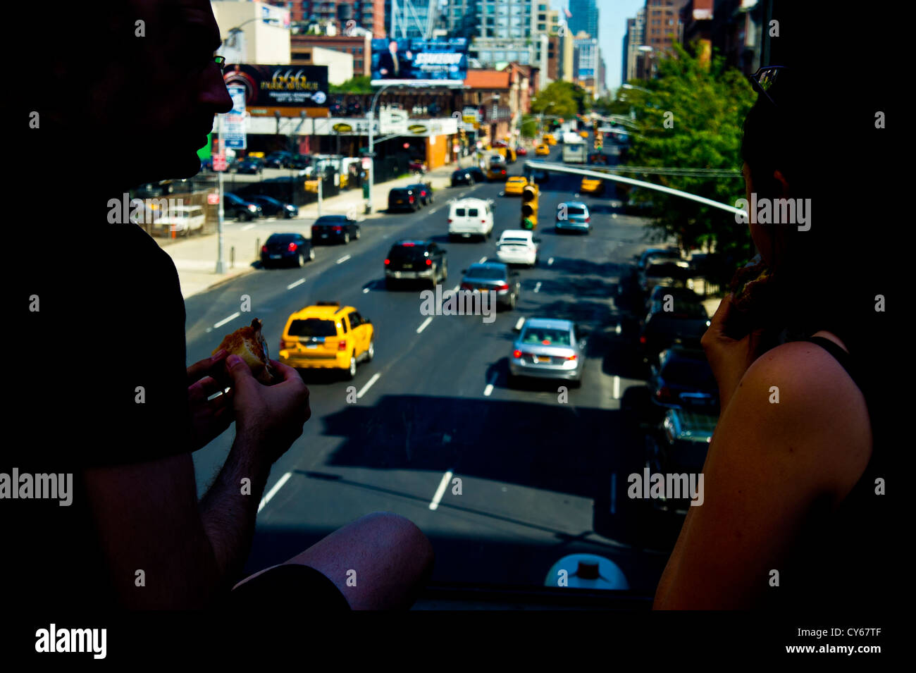 Tourists enjoy the viewing window on the High Line city park, looking ...