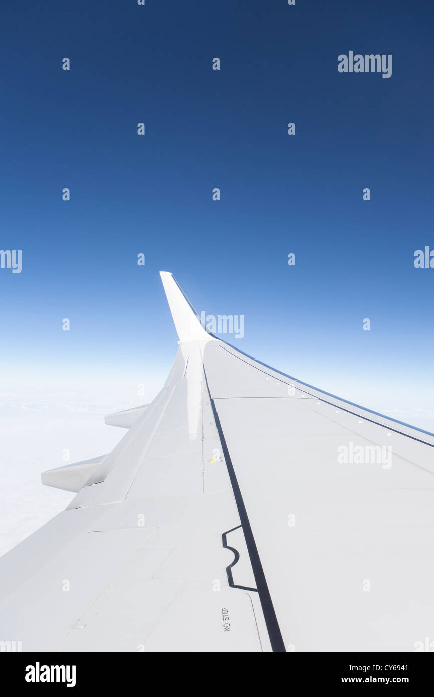 Airplane Boeing-737 wing as seen from a plane window with a bright blue ...