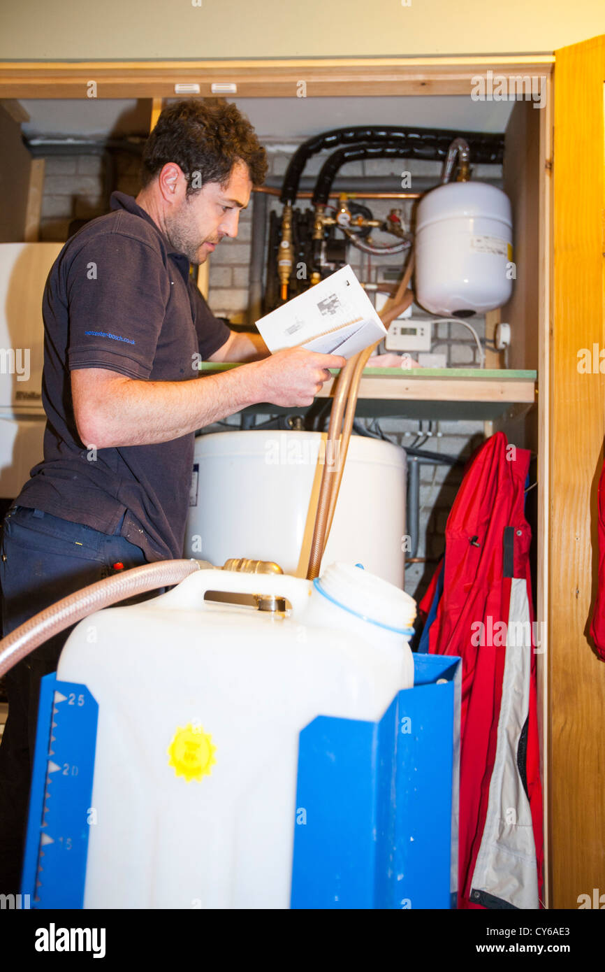 A plumber uses a machine to fill a solar thermal panel for heating ...