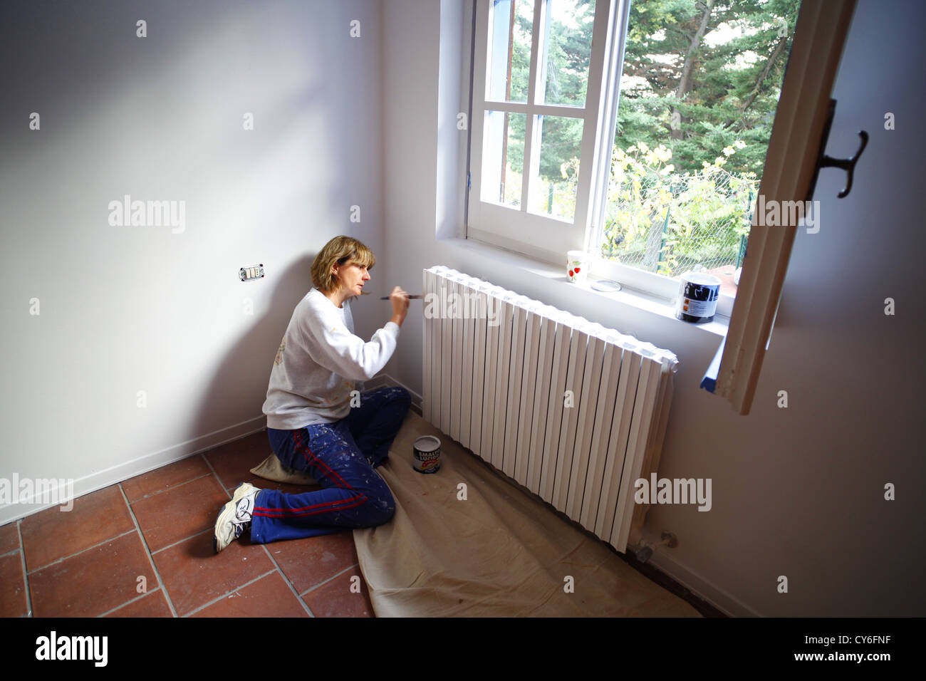 Woman painting radiator Stock Photo - Alamy