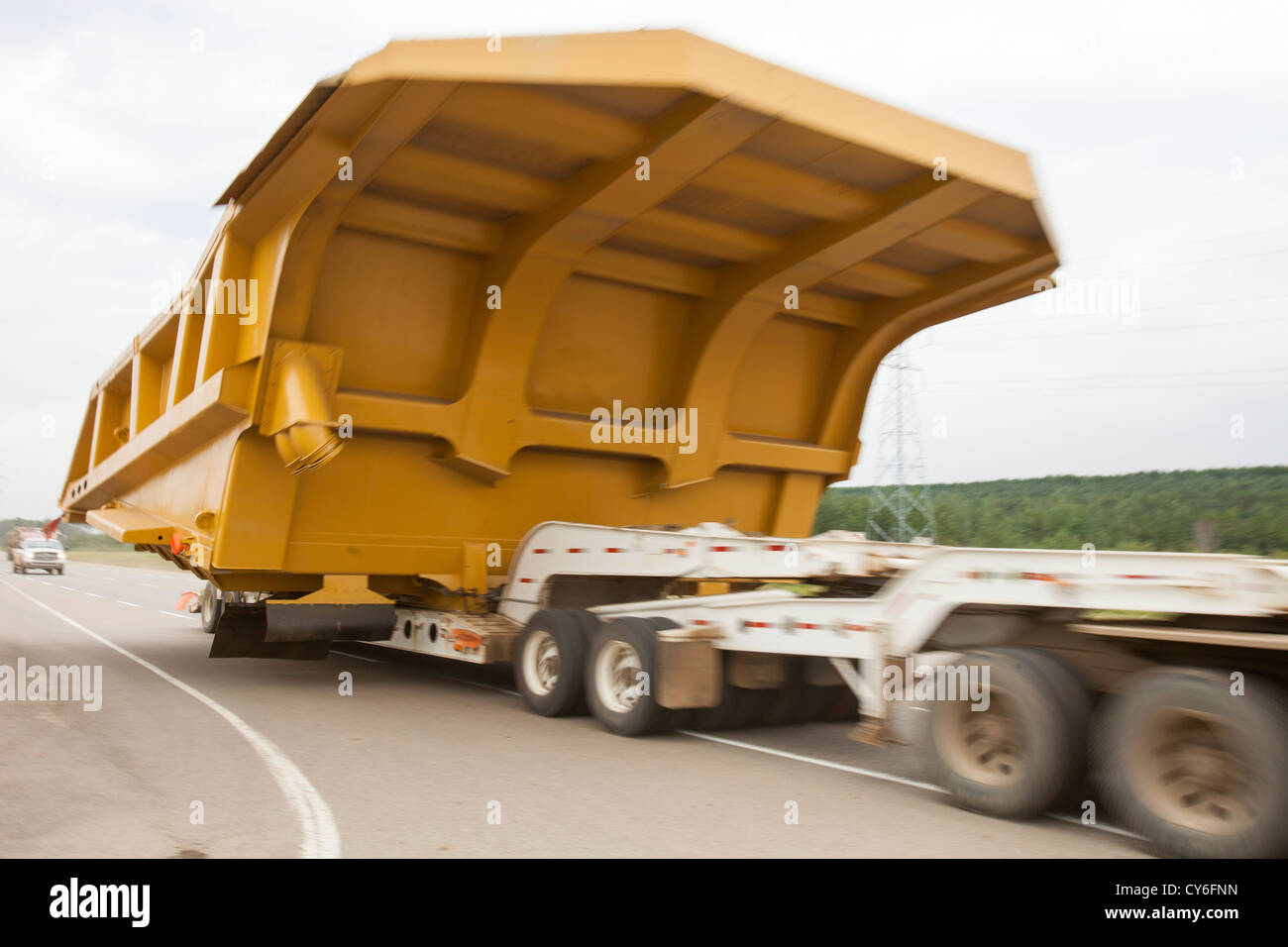 Trucks haul an oversize load, a massive dump truck used in the tar ...