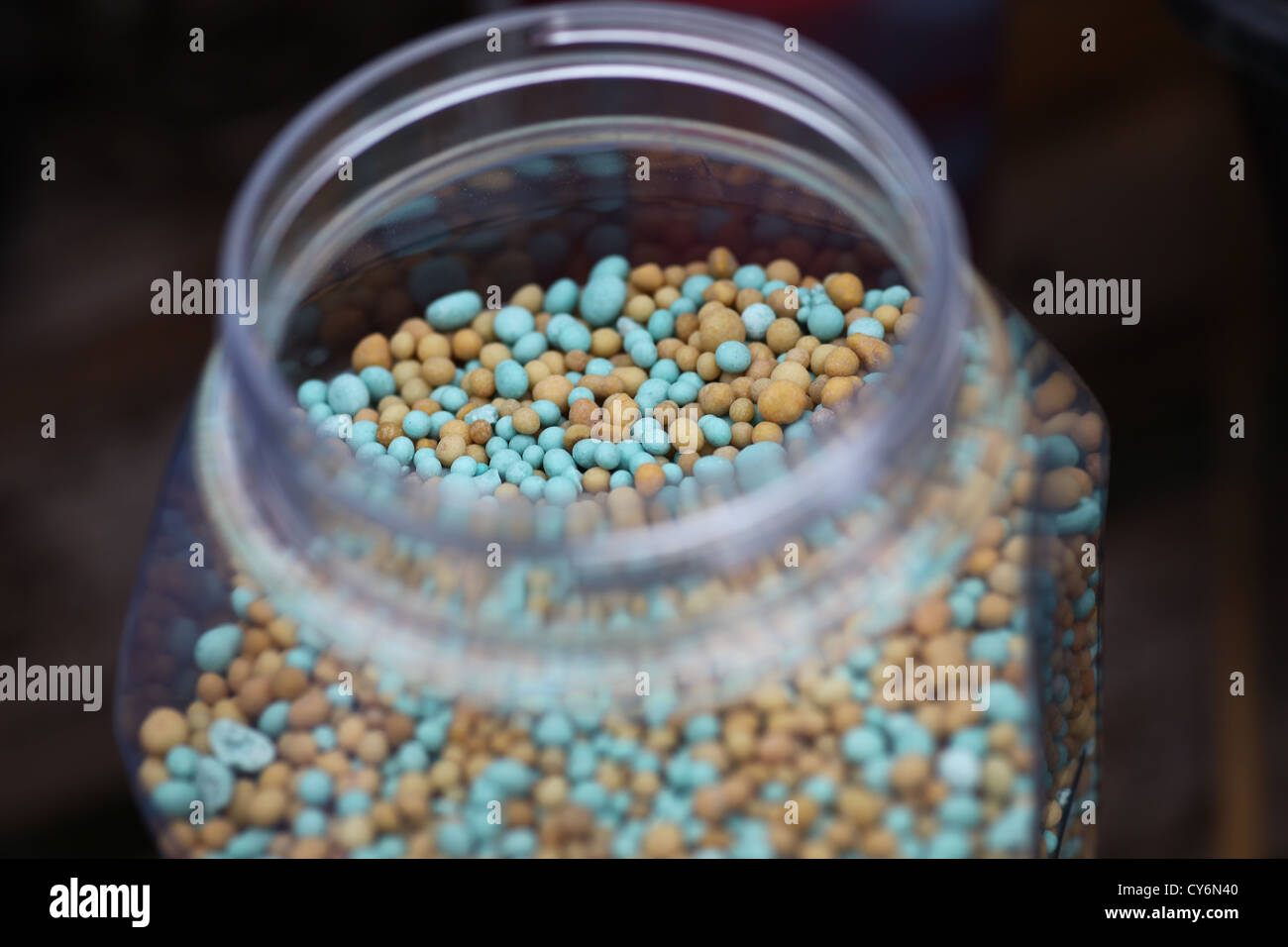 A close-up of slow release plant food fertilizer granules in a plastic ...