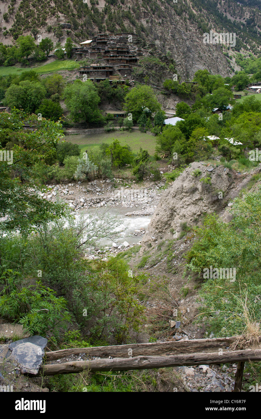 Wooden irrigation channel in front of steeply terraced Kalash village ...