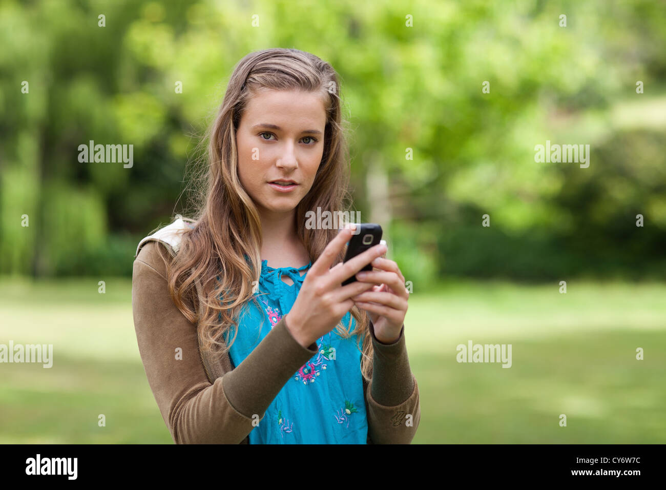 Teenage girl sending a text while looking at the camera Stock Photo - Alamy