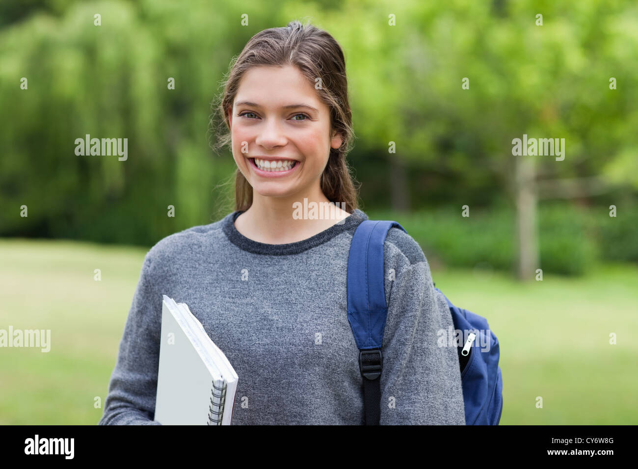 Young happy adult coming back from school while holding a notebook ...