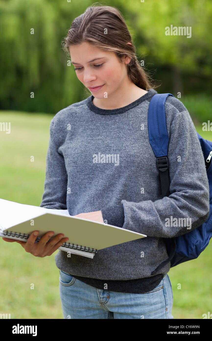Young woman reading her notebook while standing up in a park Stock ...