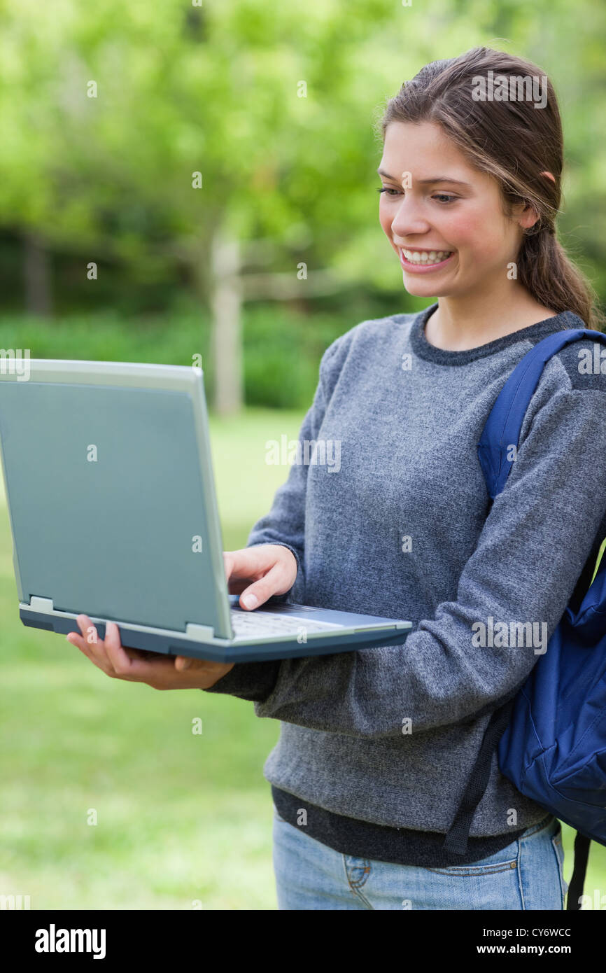 Happy student looking at the screen of her laptop while standing ...
