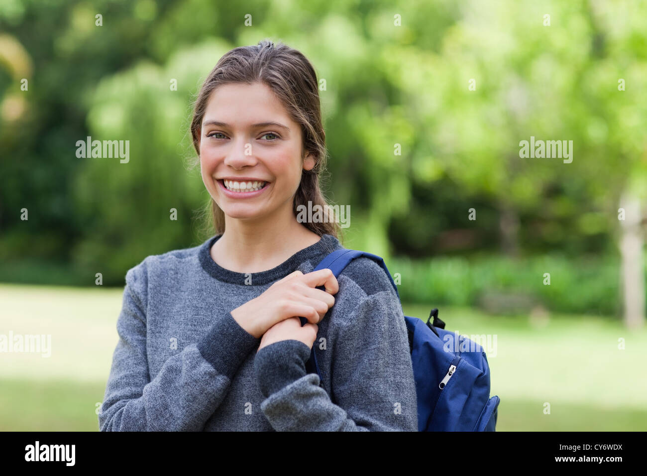 Young smiling girl standing upright in a park Stock Photo - Alamy