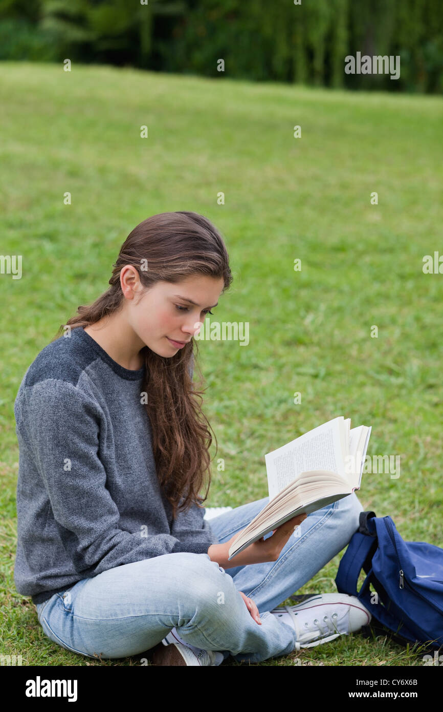 Young woman crossing her legs while reading a book Stock Photo - Alamy