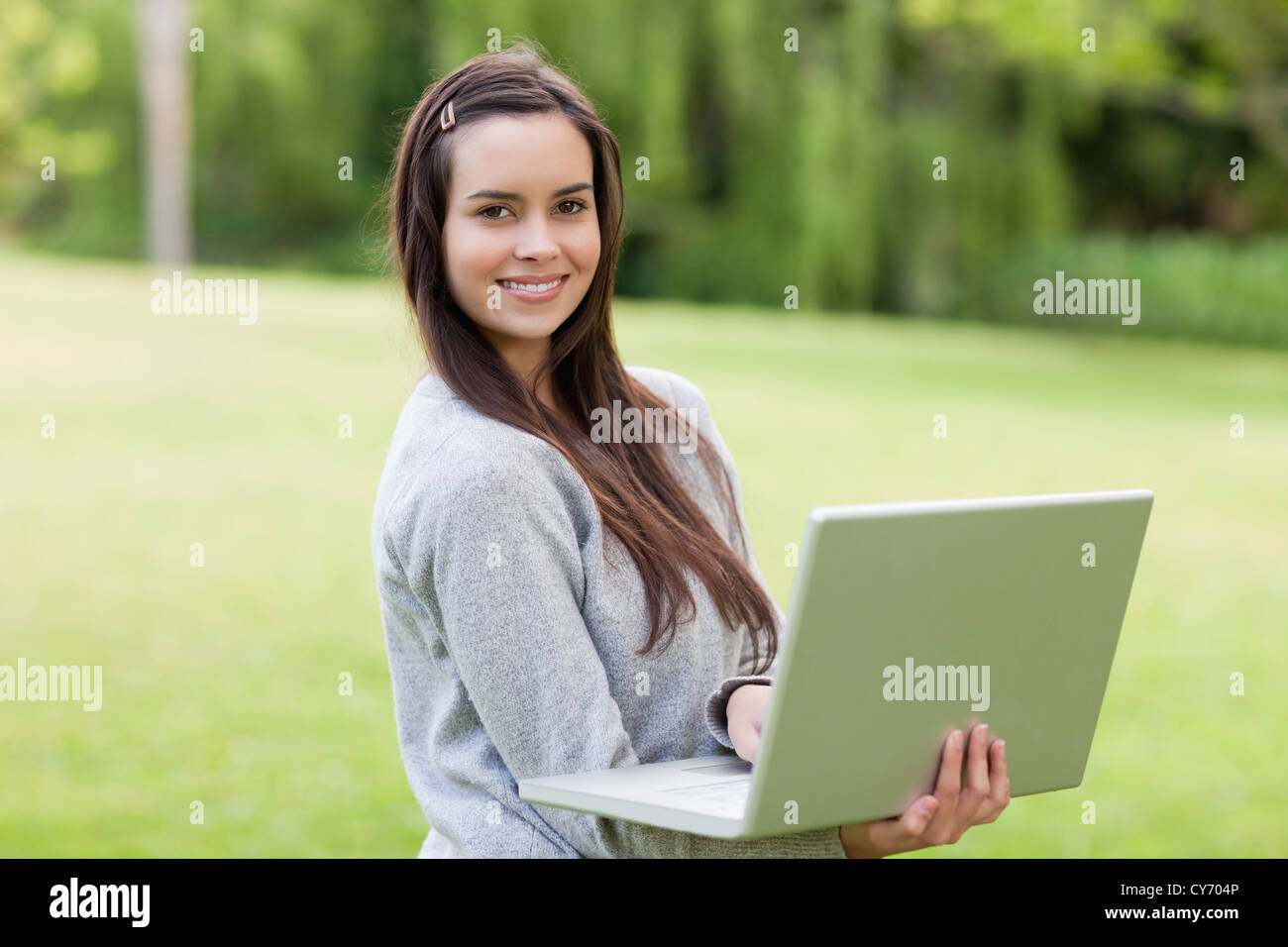Young woman standing upright in a garden while using her laptop Stock ...