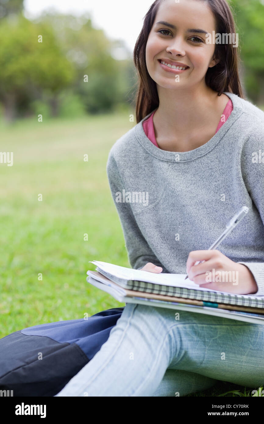 Smiling student doing her homework while sitting on the grass Stock ...
