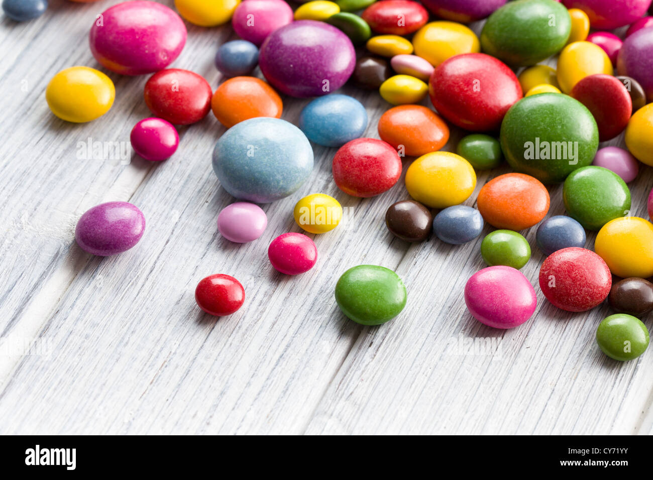 Three different sizes of colorful candies on wooden table Stock Photo ...