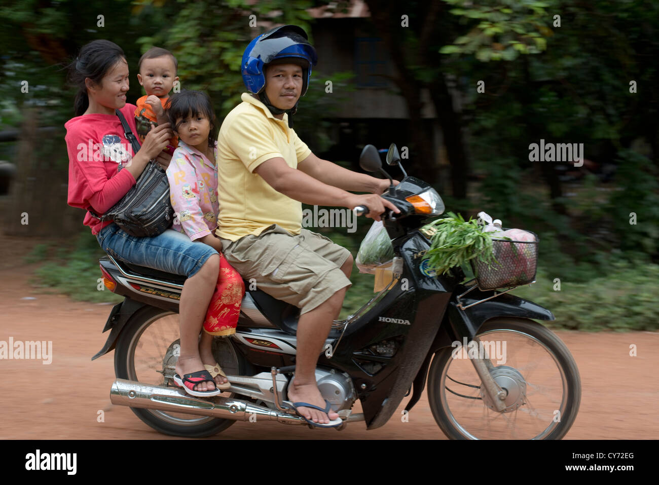 A young family pass by on their motorbike in O'Ambel village, Sisophon ...
